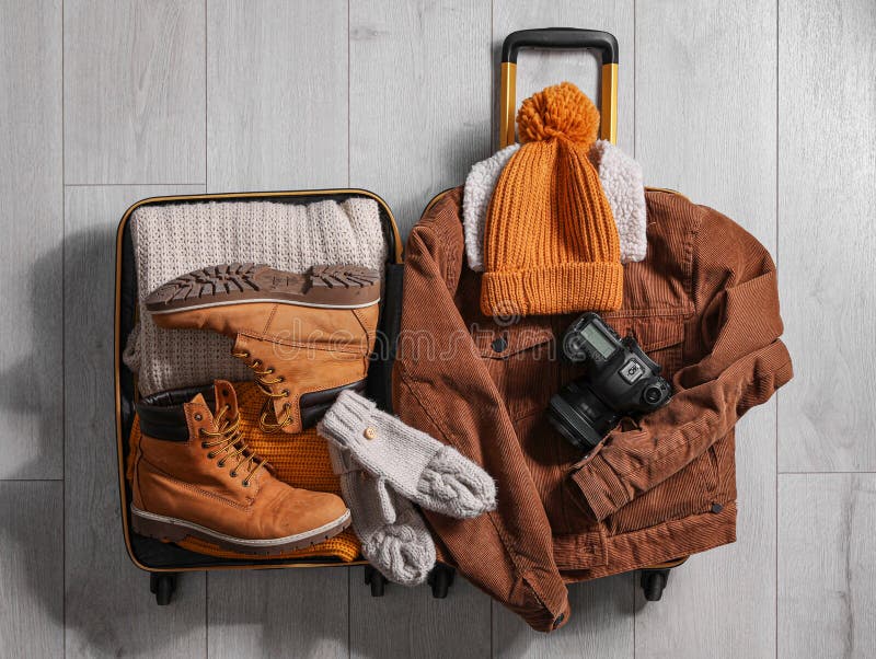 Open Suitcase with Warm Clothes and Camera on Floor, Flat Lay. Winter ...