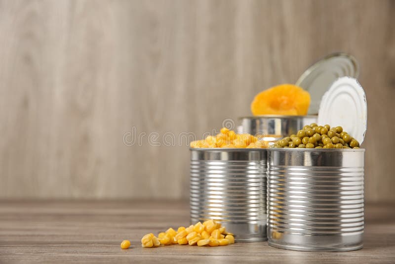 Open Tin Cans with Conserved Vegetables and Fruits on Table. Space for ...
