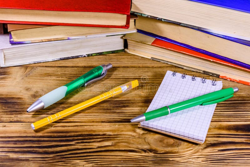 Opened Small Notepad and Ball Pens on a Wooden Table in Front of Stack ...