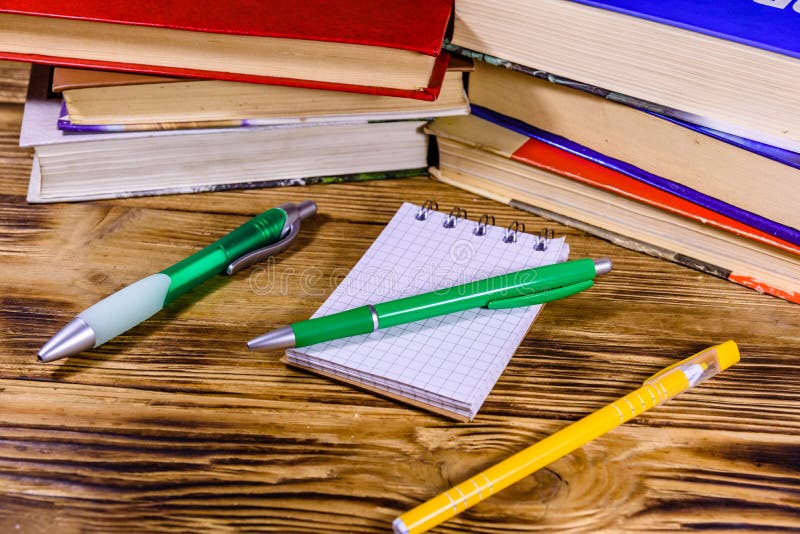 Opened Small Notepad and Ball Pens on a Wooden Table in Front of Stack ...