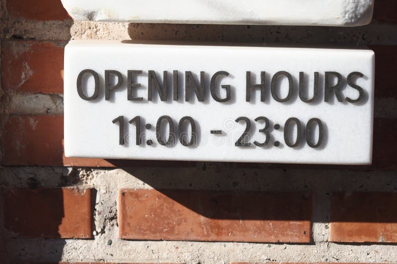 Opening Hours Displayed on a Stone Sign in a Brick Wall Stock Image ...