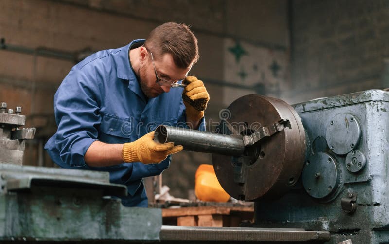 Operating the Automatic Machine. Factory Worker in Blue Uniform is ...