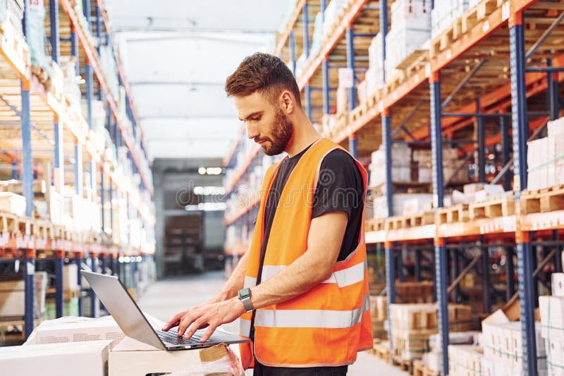 Operating the Laptop. Storage Worker is in the Warehouse with Bunch of ...