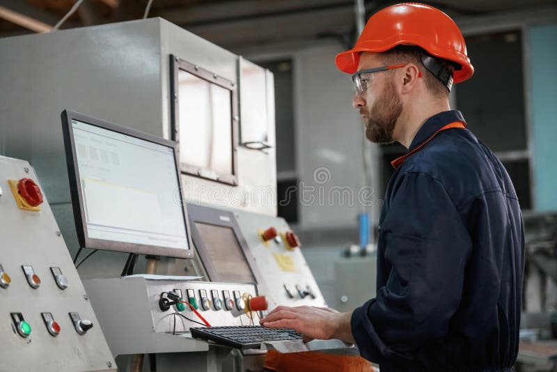 Operating the Machine. Factory Worker is Indoors with Hard Hat Stock ...