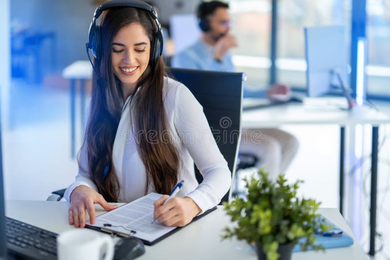 Operator Woman Wearing Headset, Multi-tasking by Taking Notes and ...