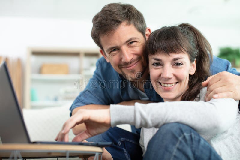 Optimistic Hugging Young Loving Couple Near Sofa Using Laptop Computer ...