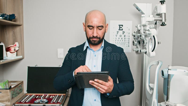 Professional Optometrist Using Tablet in Modern Office with Medical ...