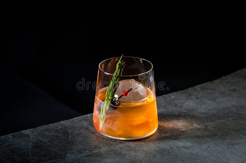 Orange Alcoholic Cocktail with a Sprig of Pine Needles and Round Ice ...