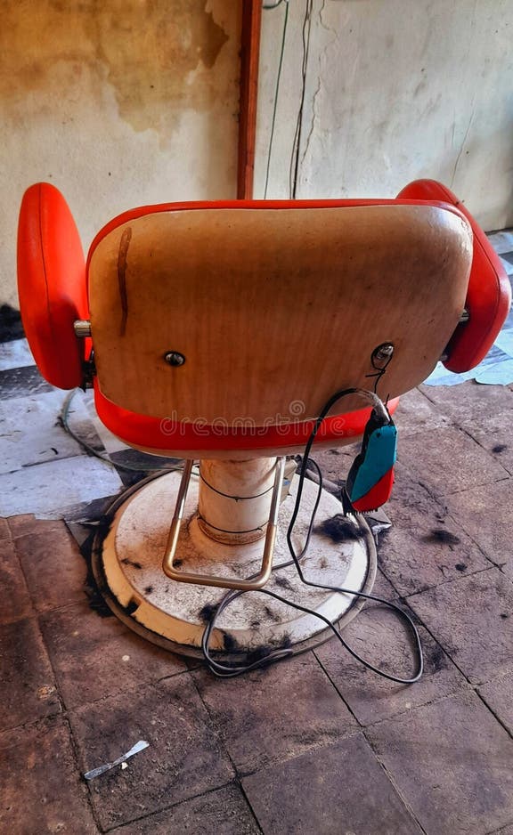 An Orange Barber Chair is Visible from Behind and a Barber Machine and ...
