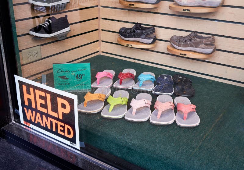 An Orange and Black Help Wanted Sign in a Storefront Window with ...