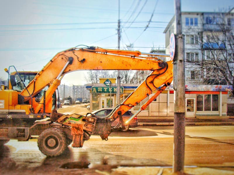 An Orange-colored Excavator Working Machine Drives Along the Road in ...