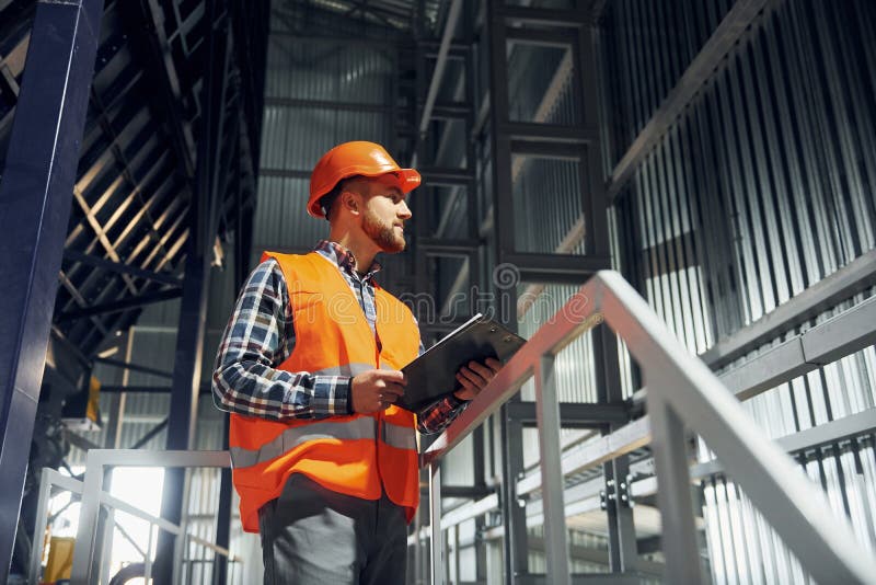 In Orange Colored Hard Hat. Construction Worker in Uniform is in the ...