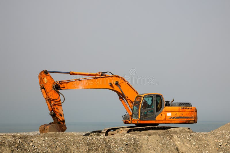 An Orange Excavator Stands on a Construction Site by the Sea, Side View ...