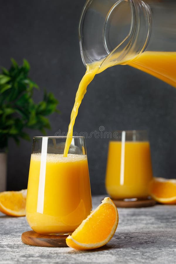 Orange Juice Pouring into Glass from Jug on Table Stock Photo - Image ...