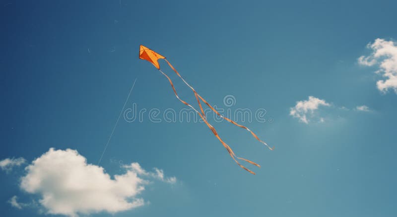 Orange Kite Flying in a Blue Sky with Fluffy White Clouds Stock ...