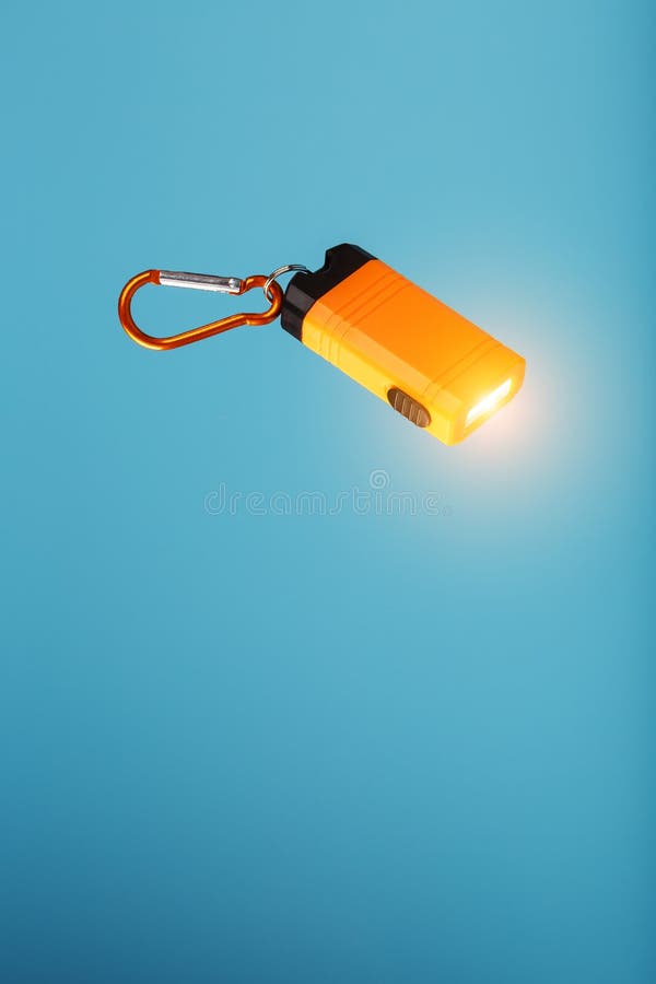 An Orange Led Flashlight with a Carabiner Glows on a Blue Background ...