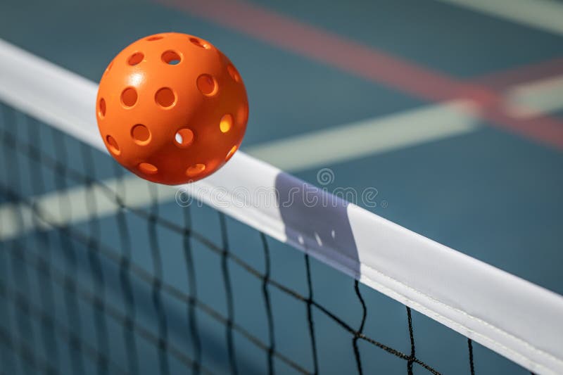 Orange Pickleball Crossing a Pickleball Net with Shadow on the Top Tape ...