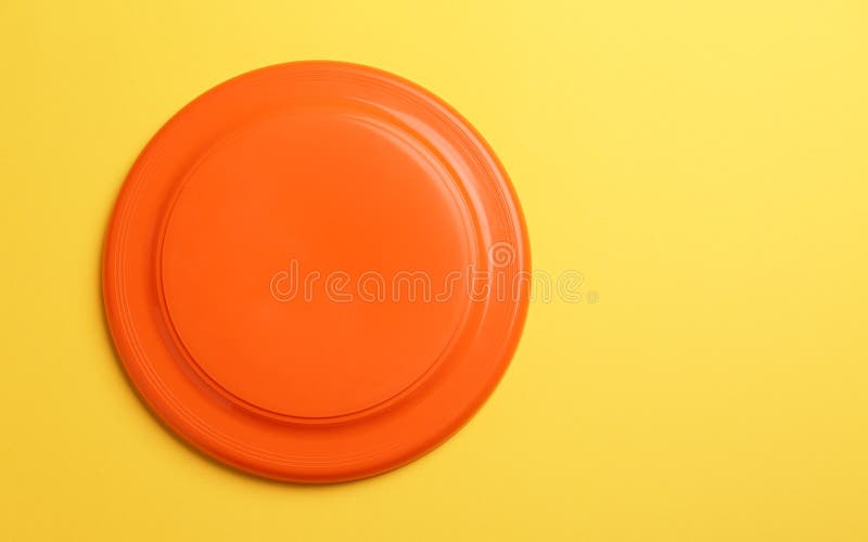 Orange Plastic Frisbee Disk on Yellow Background, Top View. Space for ...