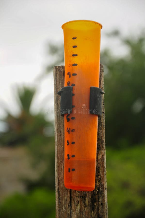 Orange Rain Gauge on Wooden Post in Rural Garden Under Cloudy Sky Stock ...