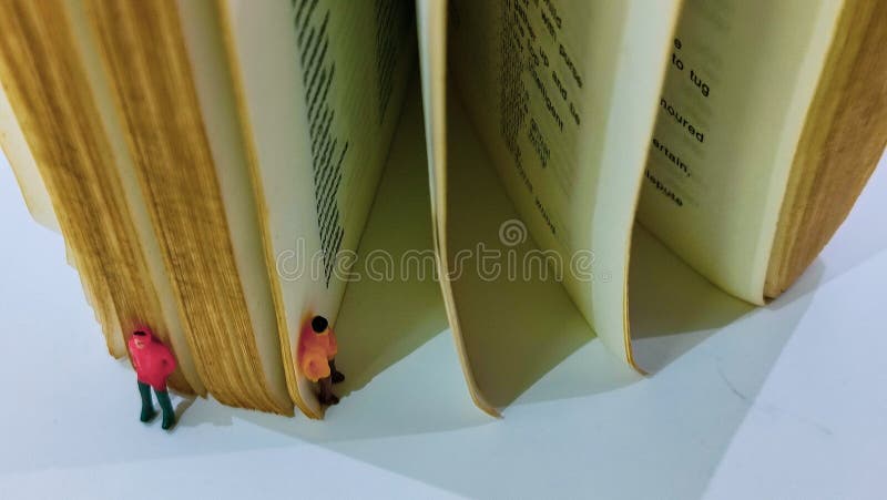 Orange-red Human Miniature on the Edge of a White Book with Blurred ...