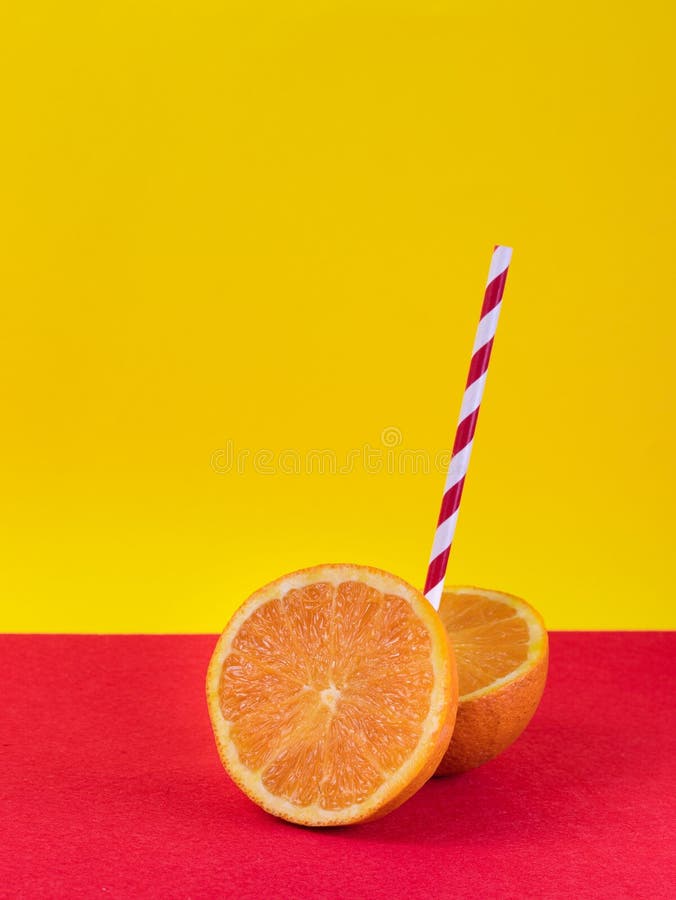 Orange Split in Half with a Straw Simulating a Soft Drink on a Yellow ...