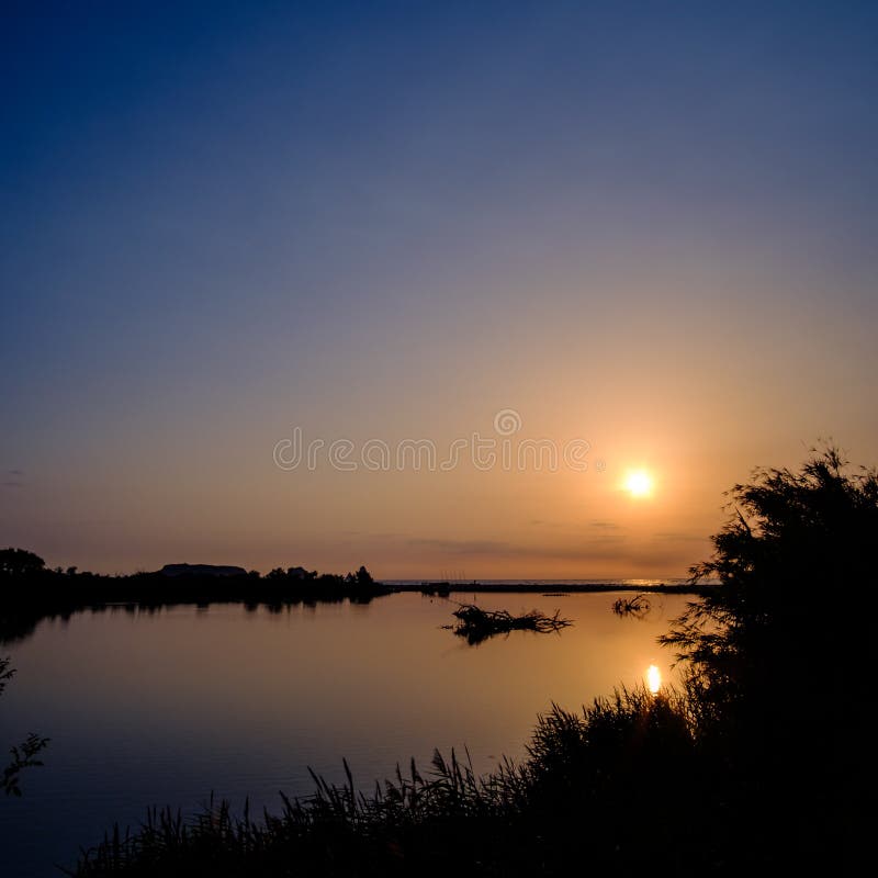 Orange Sun Rising Over River Water on Dark Silhouette Edges Stock Photo ...