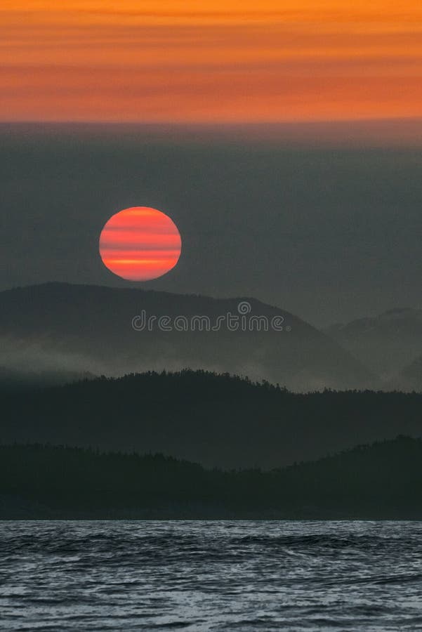 Orange Sun Setting Behind Black Mountains Stock Photo - Image of ...