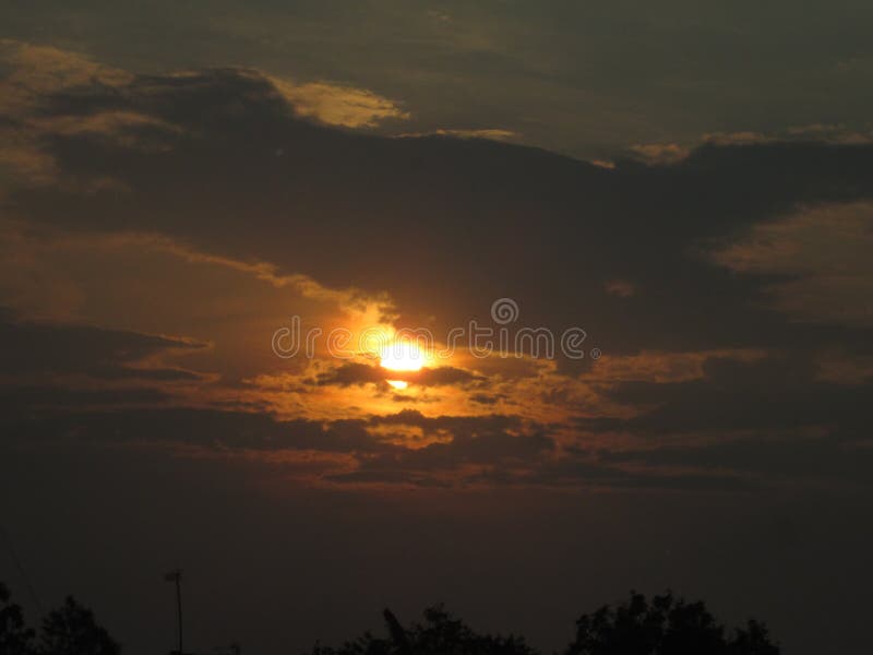 The Orange Sun Shining through the Gray Clouds Creates a Stunning View ...