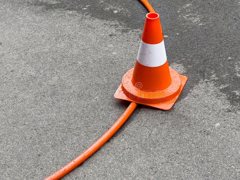 Orange Traffic Cone on Wet Asphalt with Curved Cable Stock Image ...