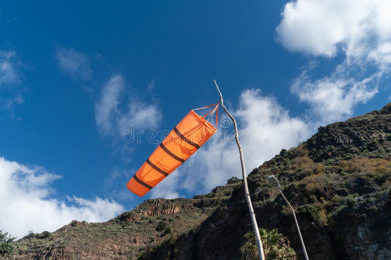Orange Windsock on a Tall Pole Against a Bright Blue Sky with Clouds ...