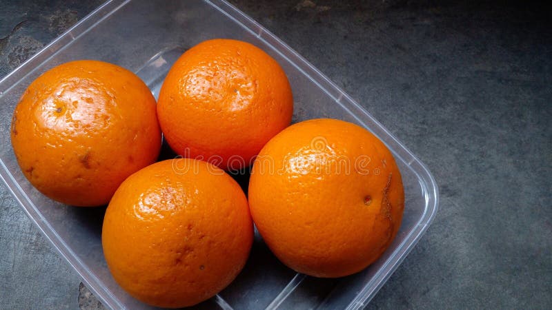 Oranges Placed in Plastic Container on a Cement Bench. High Angle View ...