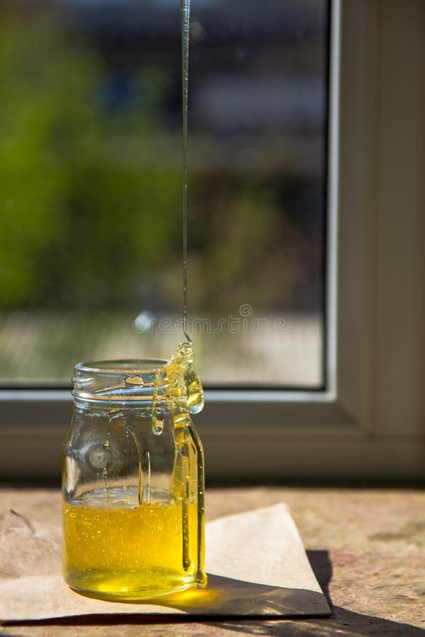 Organic Pure Honey in Jar on Window Sill. Stream of Honey Stock Photo ...