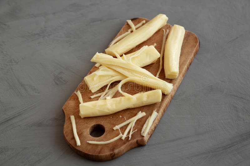 Organic String Cheese on a Rustic Wooden Board on a Gray Background ...