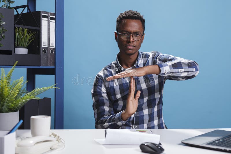 Organization Leader Gesturing Timeout Symbol with Hands while in Office ...