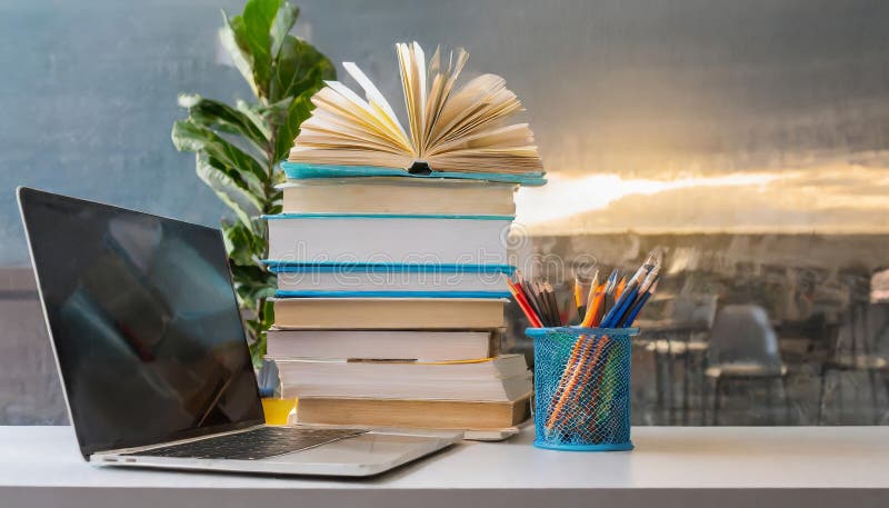 Organized Pile of Books on a Desk with a Laptop Showcasing an E-Learning Setup, Perfect for ...