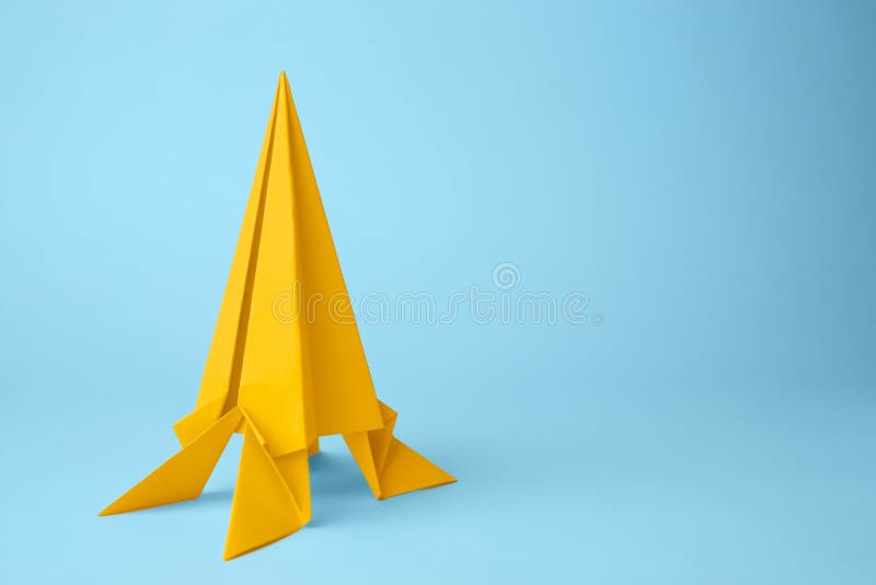 Origami Art. Handmade Yellow Paper Rocket on Light Blue Background ...