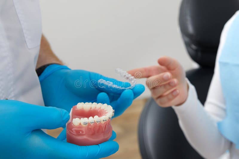 Orthodontist Showing Model of Human Jaw with Wire Braces and Aligners ...