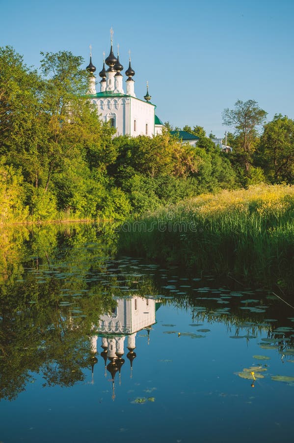 Orthodox Church with Black Domes Reflects in a River Surrounded by ...