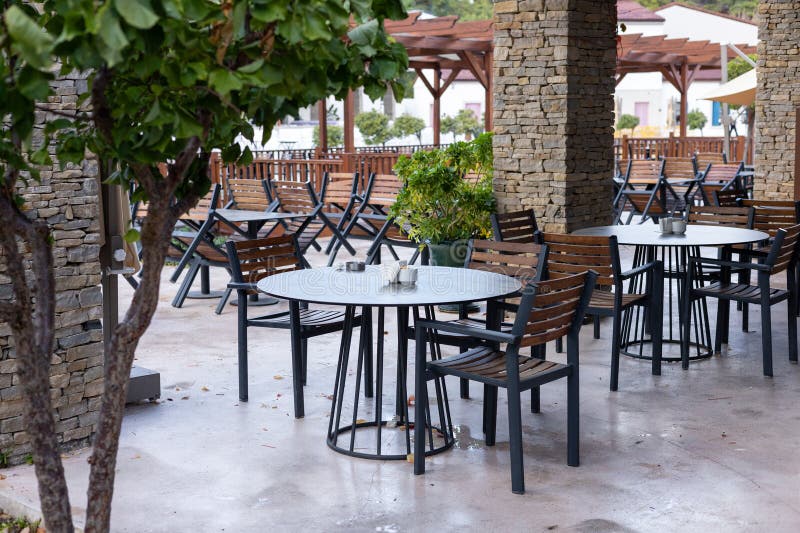 Outdoor Dining Area with Empty Tables Nestled Under Rustic Architecture ...