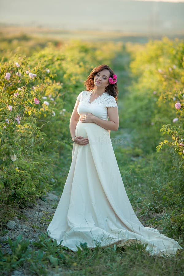 Outdoor Natural Portrait Of Beautiful Pregnant Woman In White Dress