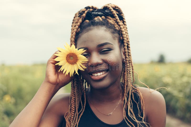 African American Girl In A Field Of Yellow Flowers At Sunset Stock