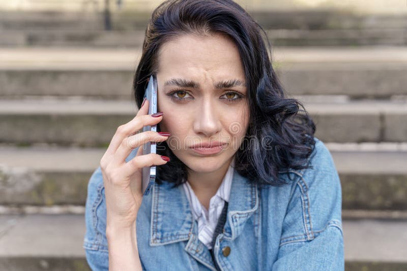 Outdoor Portrait Of An Upset Young Woman In A Denim Jacket Is Talking