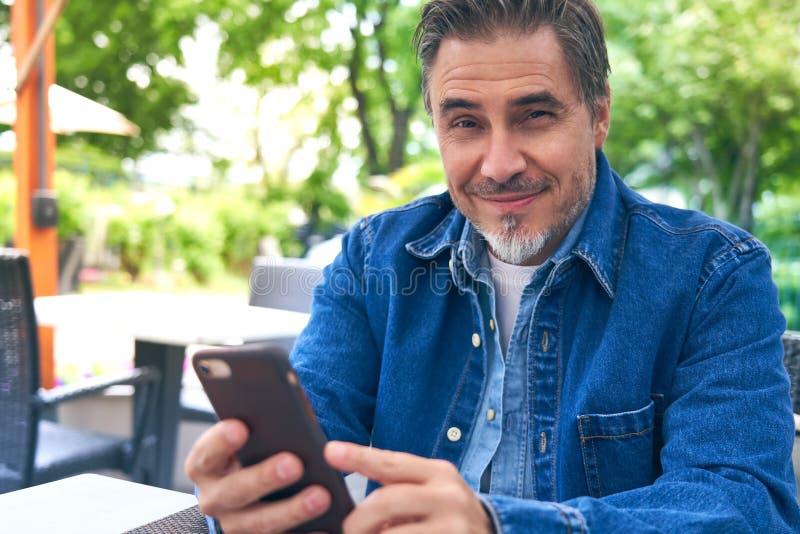 Outdoor Portrait of White Man Using Smartphone, Looking at Camera Stock ...