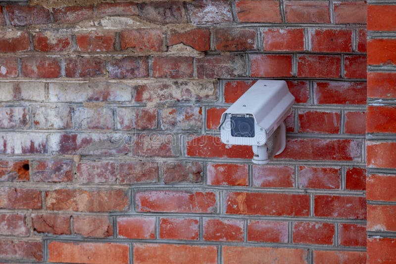 An Outdoor Surveillance Camera is Attached To the Brick Wall of the ...