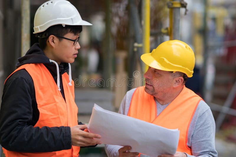 Asian Apprentice Engineer at Work on Construction Site with the Senior ...