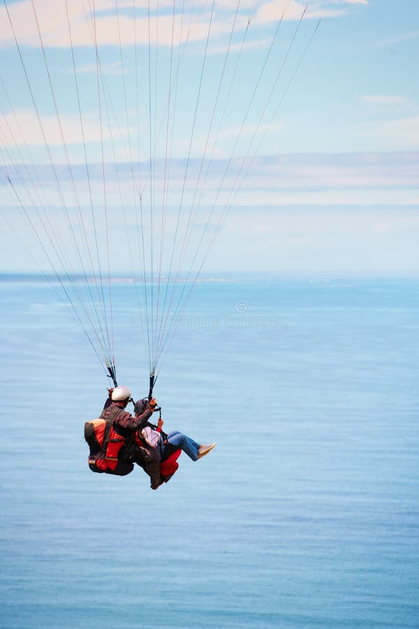 Over the Ocean. Side View of Two Young People Doing Tandem Paragliding ...