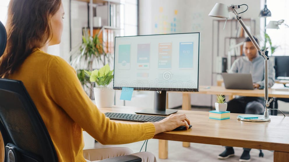 Over the Shoulder: Female Mobile Software Developer Sitting at Her Desk ...