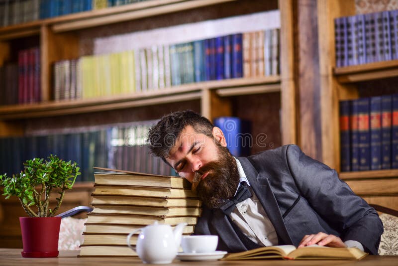 Over Worked Man Sleeping on an Open Book with Many More on the Table ...