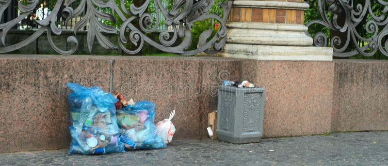 Overflowing Trash Can and Three Full Garbage Bags at the Fence of the ...