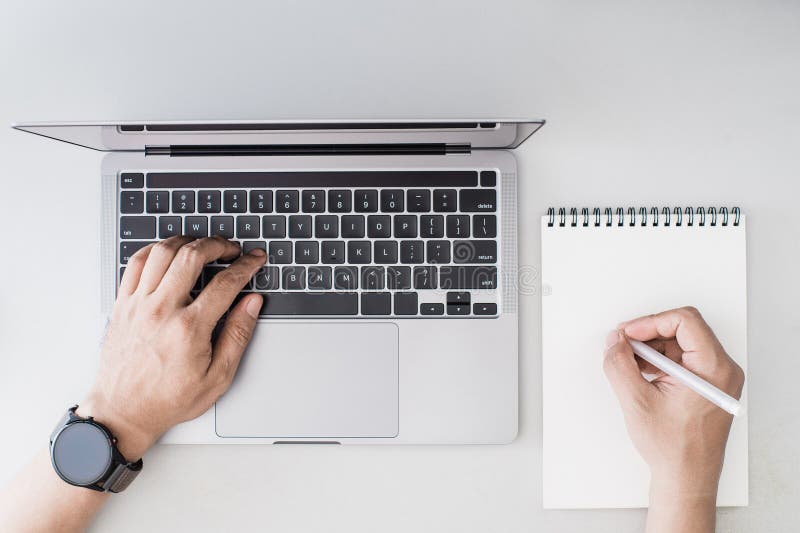 Overhead Image of Person Working on a Laptop while Writing Something on ...